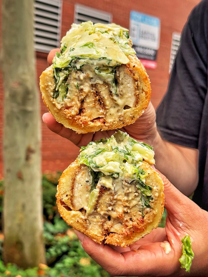 Two halves of heaven: The Chicken Cutlet sandwich with its crispy exterior and tender interior, complemented by fresh greens and that signature sauce.