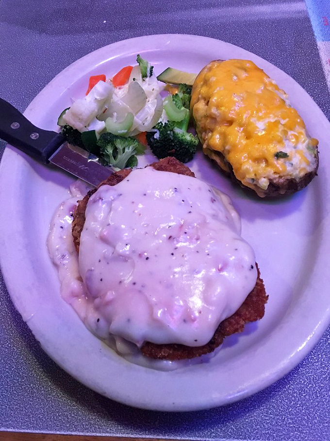 Country-fried steak smothered in peppery gravy alongside a twice-baked potato that's wearing a cheesy tuxedo. Vegetables included for plausible deniability.