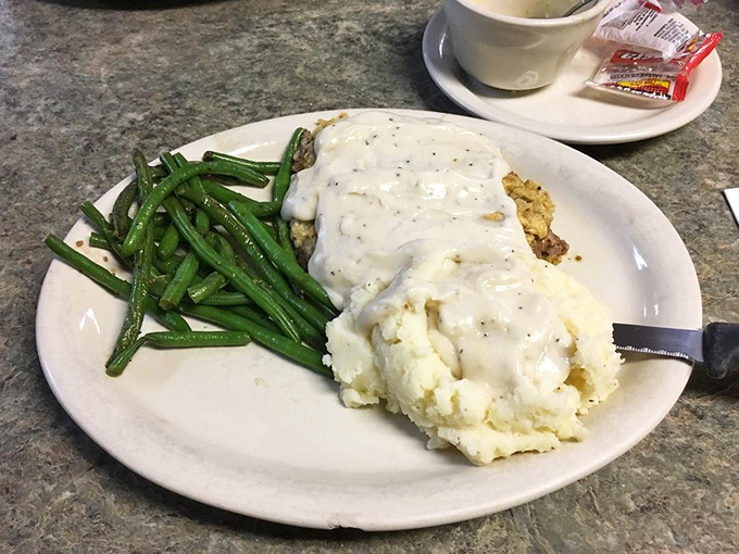 The chicken fried steak arrives with gravy cascading over the edges, a masterpiece of crispy exterior and tender interior that demands your full attention.