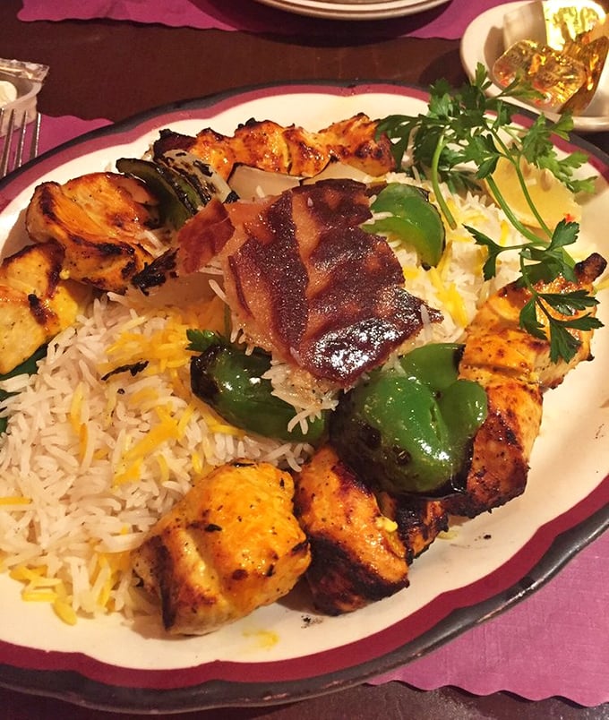 Golden-grilled chicken kebabs rest majestically on fluffy rice, proving that simple perfection never goes out of style.
