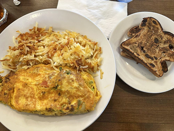 This isn't just an omelette&mdash;it's a masterpiece of morning architecture with perfectly crisp hash browns and raisin toast that deserves its own fan club.