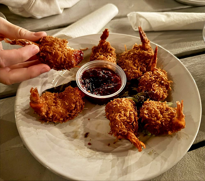 These coconut shrimp arrive looking like golden treasures, each one a crispy passport to flavor paradise.