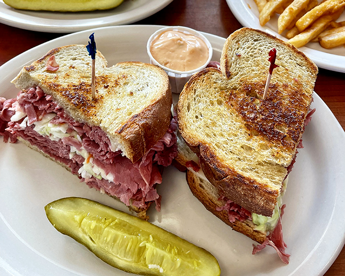 This isn't just a sandwich; it's a skyscraper of corned beef engineering. The pickle stands guard like it knows what treasure it's protecting.