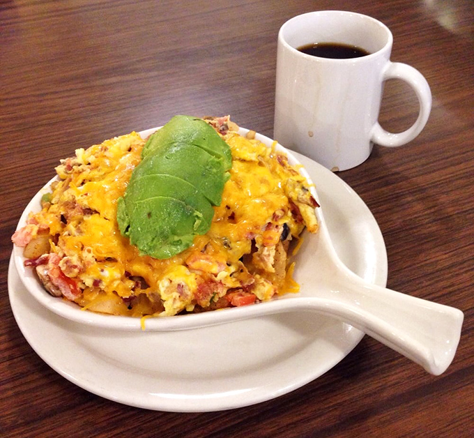A mountain of breakfast goodness topped with perfectly ripe avocado. The coffee cup stands by, knowing its supporting role is crucial to the experience.