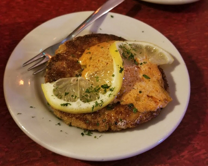 A crab cake that doesn't hide behind fillers, proudly wearing its golden crust like a medal. Those lemon slices aren't garnish&mdash;they're essential supporting actors.
