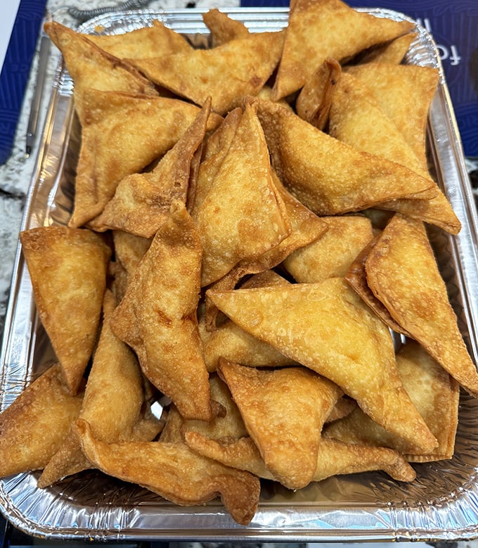 Golden-fried crab rangoon triangles pile high like edible treasure. That satisfying crunch followed by creamy filling is worth every calorie.