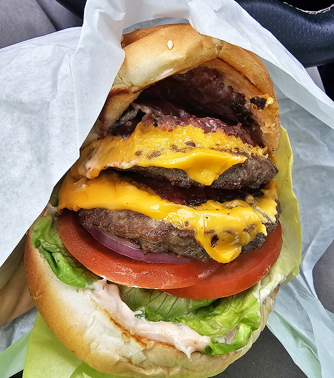 This isn't just a burger; it's a skyscraper of beef, cheese, and fresh veggies that requires both hands and possibly a building permit.