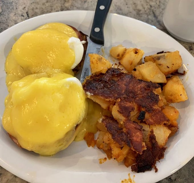 Eggs Benedict done right—hollandaise cascading down like a yellow waterfall of happiness, with home fries crisped to perfection. This is why breakfast was invented.