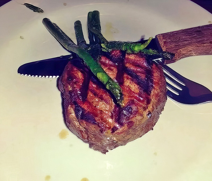 The filet mignon stands tall like a meaty monument to perfection, with asparagus soldiers standing guard against vegetable deficiency.