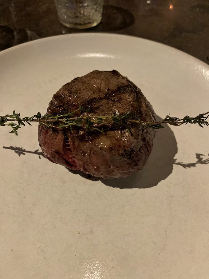 Simplicity at its finest: a perfectly seared filet mignon with a sprig of thyme that's not just garnish&mdash;it's a promise of flavor.