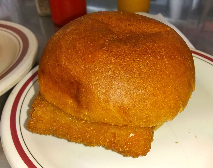 The fish sandwich arrives like a golden-fried postcard from comfort food heaven, nestled in a bun that's somehow both sturdy and cloud-like.