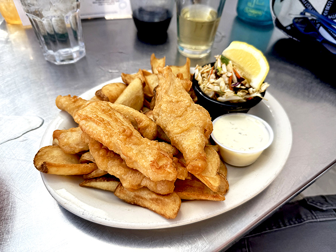 Golden-battered fish that shatters with each bite, revealing steamy flakes of perfection beneath. The coleslaw provides the perfect acidic counterpoint to this crispy symphony.