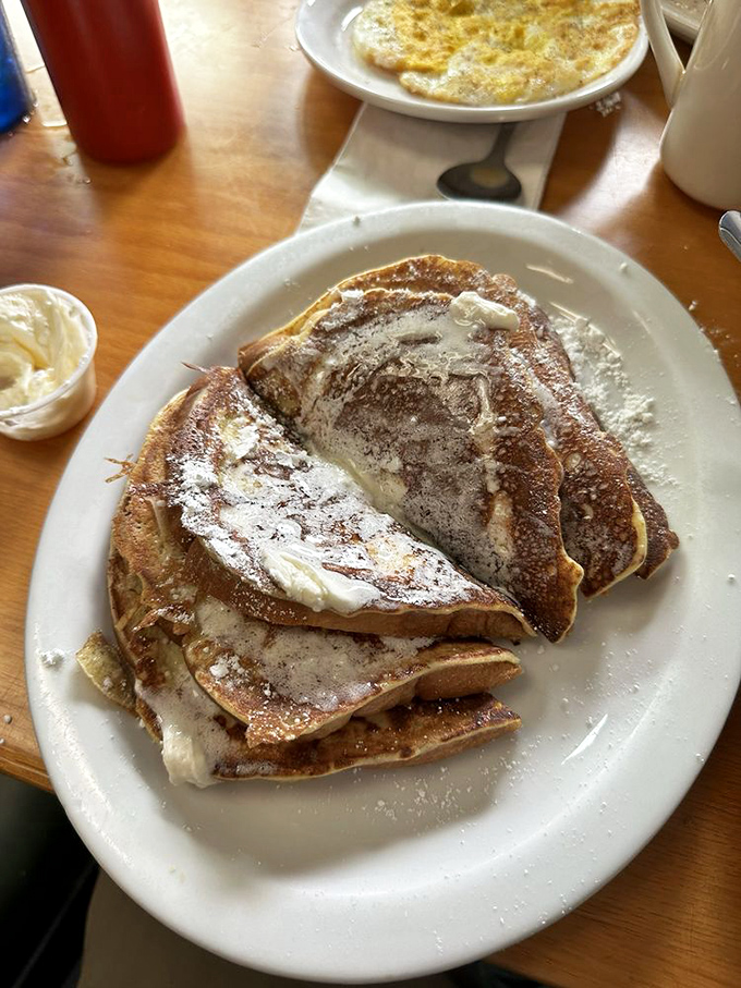 French toast that would make your grandmother weep with joy. Crispy edges, custardy centers, and enough powdered sugar to leave evidence on your shirt.