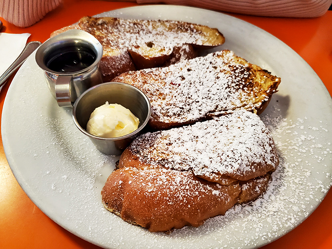 French toast that's had a proper powdered sugar snowfall. The butter and syrup waiting patiently in their metal sidecars for the main event.