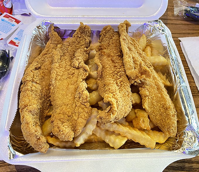 Golden-battered fish that would make a British pub jealous, perched atop a mountain of fries like royalty on a throne.