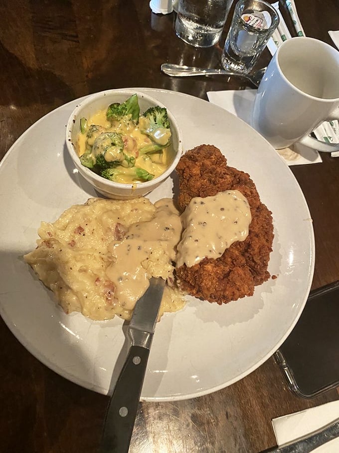 Southern comfort on a plate: golden-fried pork chop with creamy gravy alongside mashed potatoes and vegetable medley.