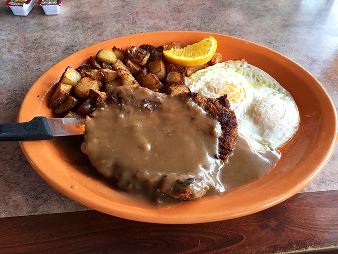 Country fried steak swimming in gravy like it's taking a luxurious bath, with crispy potatoes standing by for the inevitable dipping expedition.
