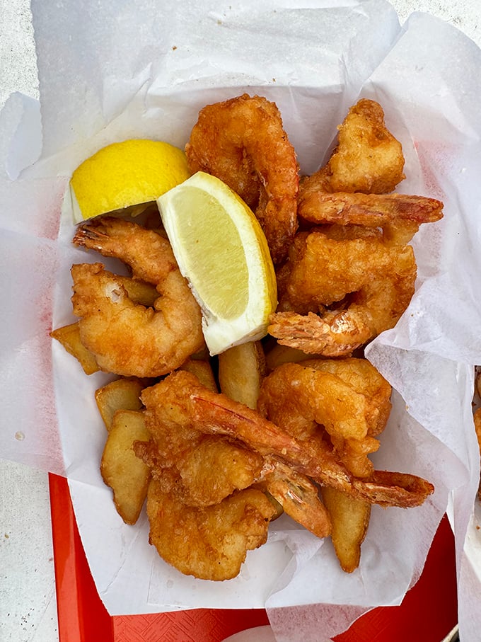 Golden-battered shrimp and fries nestled in paper&mdash;seafood at its most honest. That lemon wedge isn't just garnish; it's essential equipment.