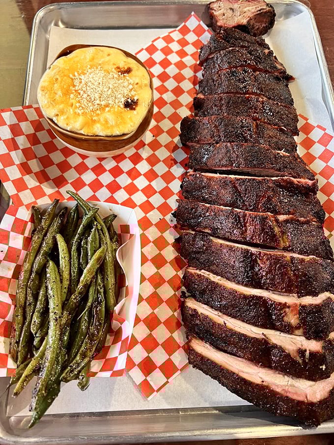 A rack of ribs that would make Fred Flintstone weep with joy, flanked by mac and cheese that's clearly not from a box. This is BBQ artistry on a metal tray.