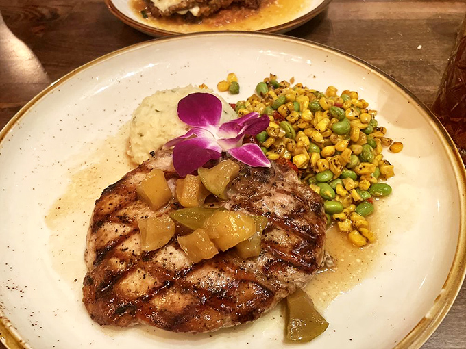 Behold the star of our show: the grilled pork chop that launched a thousand road trips. That caramelized exterior gives way to juicy perfection beneath.
