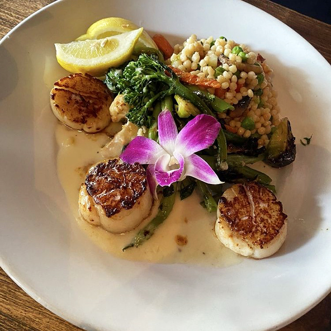 These perfectly seared scallops aren't just dinner, they're edible art &ndash; complete with an orchid garnish that's both "fancy restaurant" and "I'm about to have a religious experience."