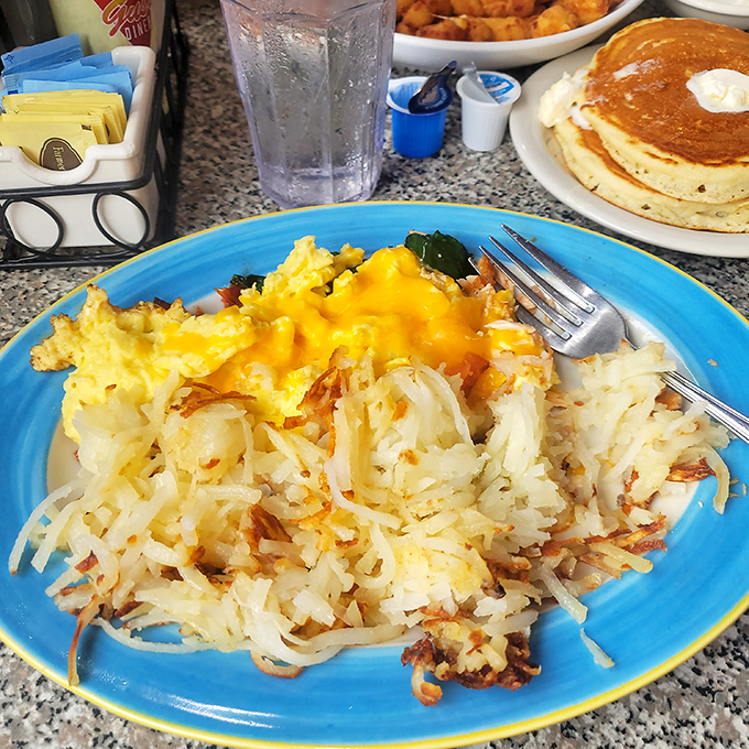 Golden hash browns that crackle with each bite, crowned with melted cheese and paired with fluffy scrambled eggs &ndash; breakfast nirvana on a blue plate.