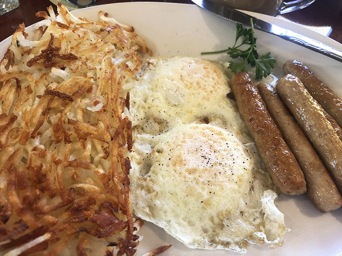 The holy breakfast trinity: crispy hash browns with the perfect golden crust, eggs with runny yolks, and sausage links that snap when you bite them.