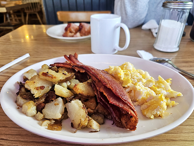 The holy trinity of breakfast: perfectly crispy home fries, eggs with just-right yolks, and bacon that should have its own fan club.