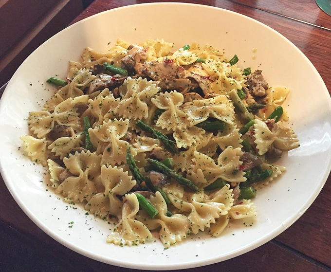 The Jerk Chicken Pasta performs culinary diplomacy between Italy and Jamaica with bow-tie pasta, asparagus, and seasoned chicken in a harmony that shouldn't work but absolutely does.