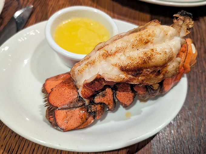 The lobster tail arrives like royalty on its throne of shell, accompanied by drawn butter that's practically liquid gold.