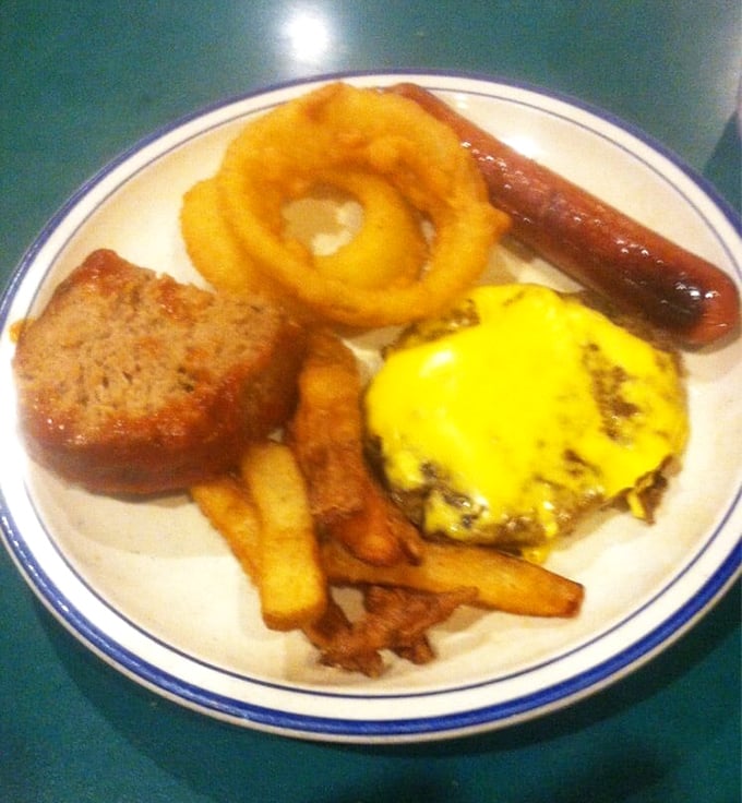 Breakfast of champions: a golden onion ring crowns a cheeseburger while meatloaf and fries stand by like loyal sidekicks ready for action.
