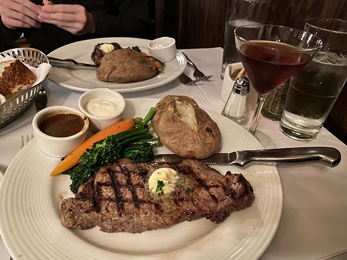 This isn't just a steak; it's a masterpiece of meat, complete with all the supporting actors: a fluffy baked potato, vibrant vegetables, and a perfectly mixed cocktail.