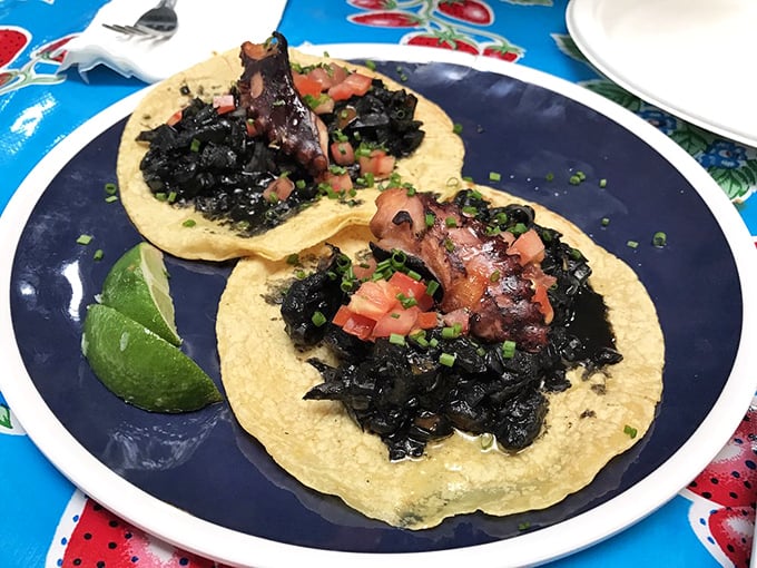 The legendary octopus tacos arrive dramatically on golden tortillas, their tentacles nestled in inky blackness&mdash;like the ocean's most delicious secret finally revealed.