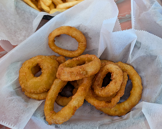 Golden, crispy onion rings that shatter with each bite, proving that sometimes the supporting actors deserve their own standing ovation.
