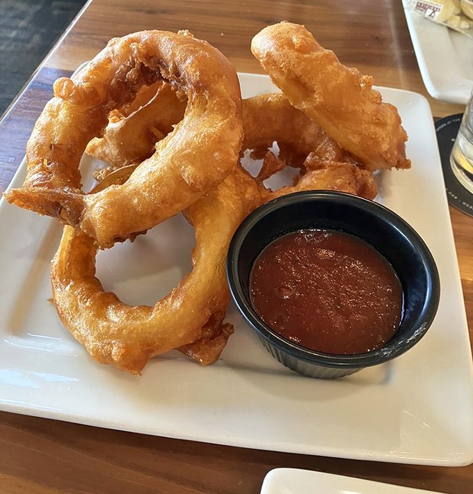 Golden-brown onion rings that shatter with each bite, paired with a dipping sauce that makes you wonder why you'd ever eat them any other way.