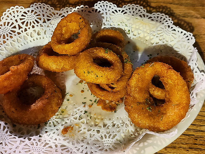 Golden-fried onion rings arrive on delicate doilies &ndash; a touch of Southern gentility for a humble dish elevated to crispy perfection.