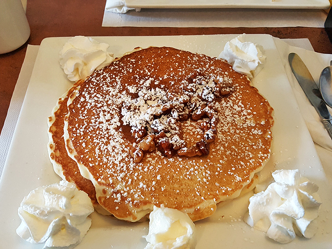A pancake so perfectly golden and fluffy, it's practically wearing a halo of powdered sugar and whipped cream.