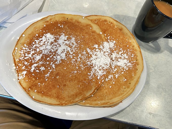 Pancakes so perfectly golden they deserve their own spotlight, dusted with powdered sugar that melts into each warm, fluffy bite.