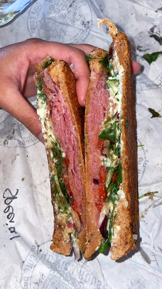 This isn't just a pastrami sandwich; it's an architectural marvel of meat, veggies, and bread that demands to be admired before it's devoured.