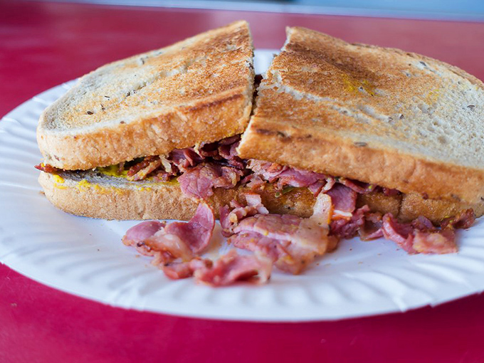 This isn't just a sandwich; it's a pastrami masterpiece where toasted bread barely contains the rebellion of smoky, pink perfection.