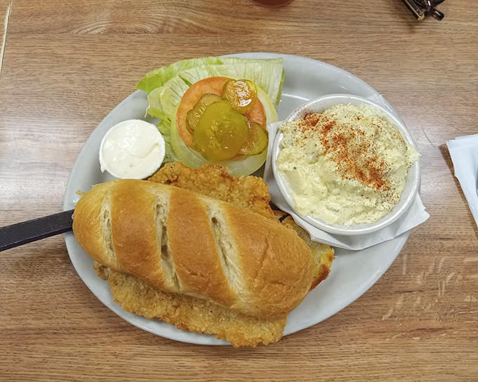 The legendary pork tenderloin sandwich in all its glory. Like a crispy, golden frisbee of happiness that refuses to acknowledge the boundaries of its bun.