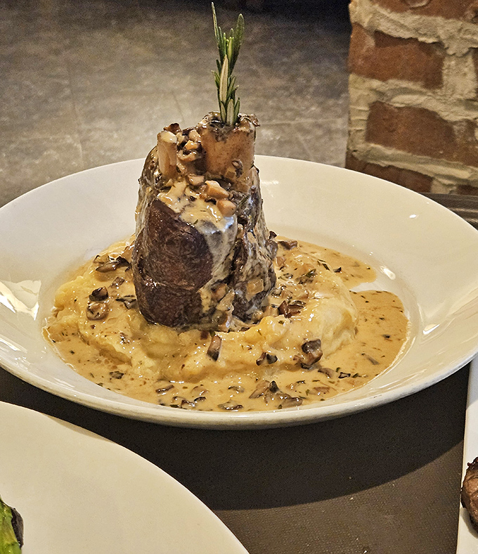 A tower of flavor! This bone-in pork shank rises majestically from a sea of creamy risotto, crowned with a sprig of rosemary.