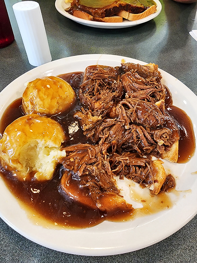 The pot roast falls apart with just a glance, swimming in gravy alongside golden-topped biscuits that practically beg for a starring role.