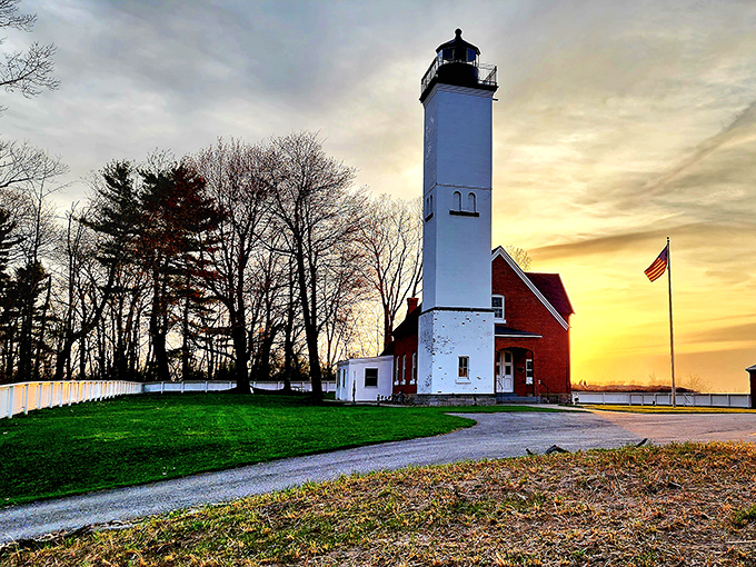 The Presque Isle Lighthouse stands tall against a sunset canvas, its white tower a beacon of maritime history since 1872.