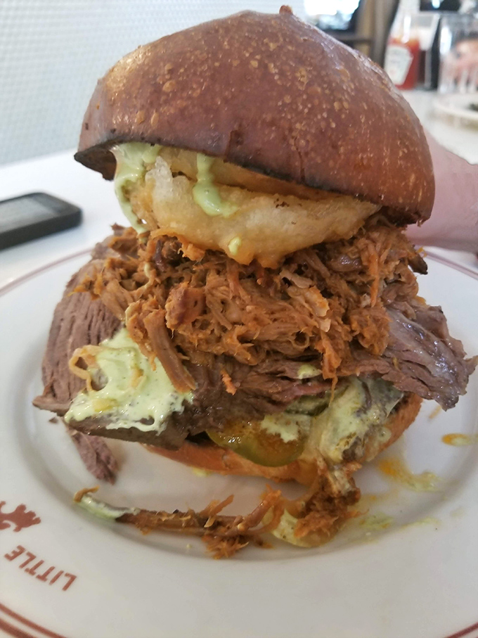 Behold the sandwich that requires both hands and a strategy. Layers of pulled pork and pickles create a towering masterpiece of lunchtime engineering.