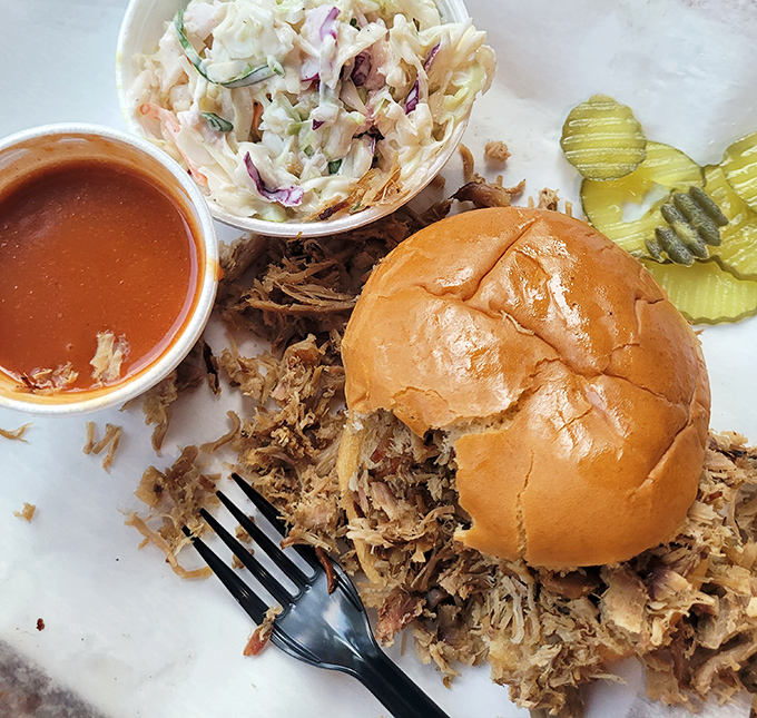 Coleslaw, sauce, and perfectly pulled pork create the holy trinity of BBQ sandwiches. The pickle chips aren't just garnish—they're the acidic counterpoint this masterpiece demands.