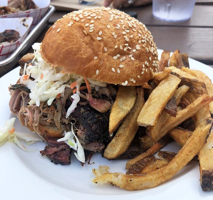 This isn't just a sandwich; it's an engineering marvel. Pulled pork piled high with slaw on a sesame bun, with fries that deserve their own fan club.