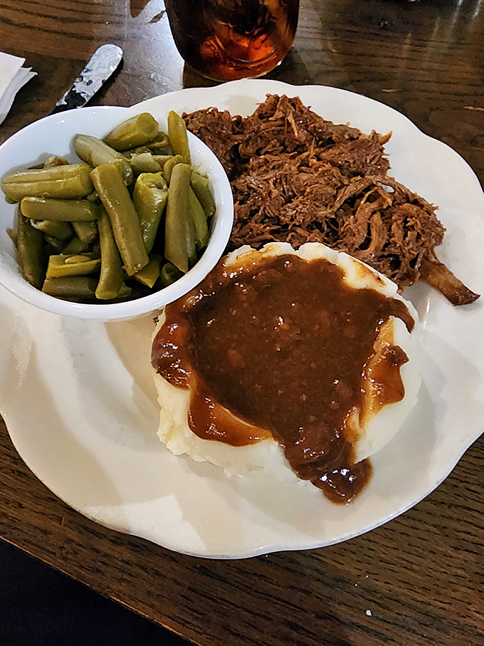 Comfort on a plate – tender roast beef with gravy cascading over mashed potatoes like a delicious waterfall, with green beans standing by for moral support.