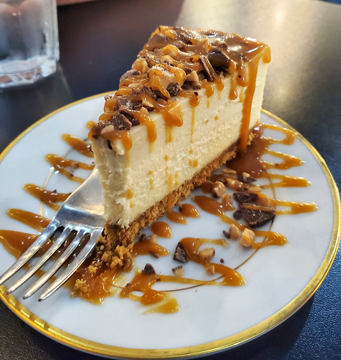 The fork stands ready for its noble purpose as rivers of caramel cascade over a landscape of cheesecake that demands to be savored slowly.