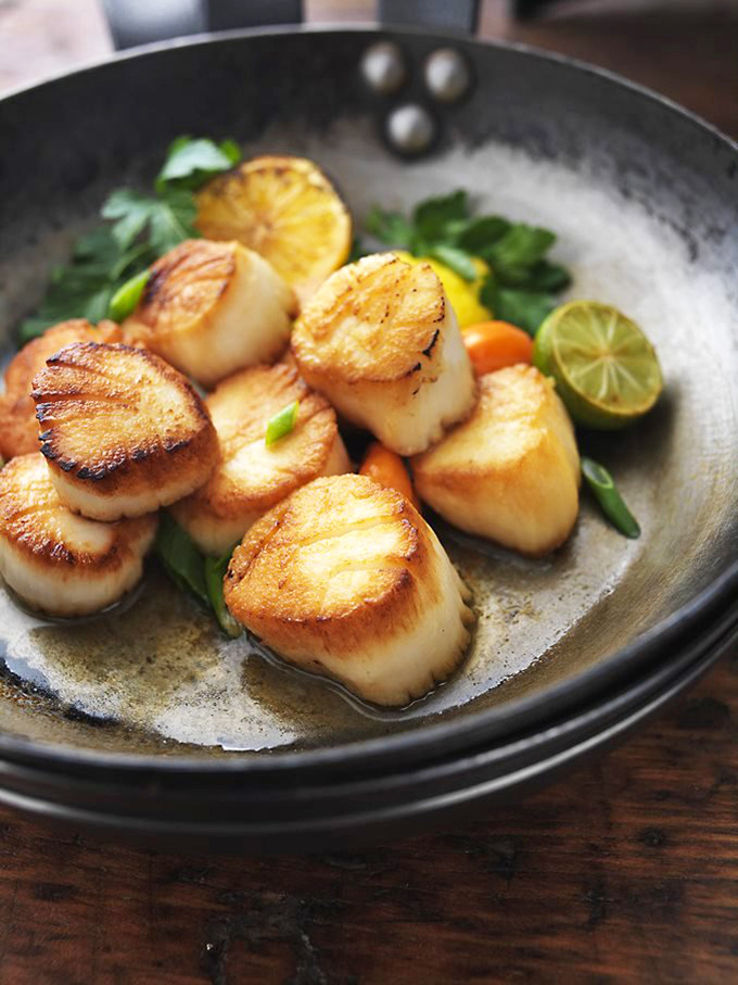 These golden-seared scallops aren't just seafood; they're buttery little islands of joy in a citrus archipelago.